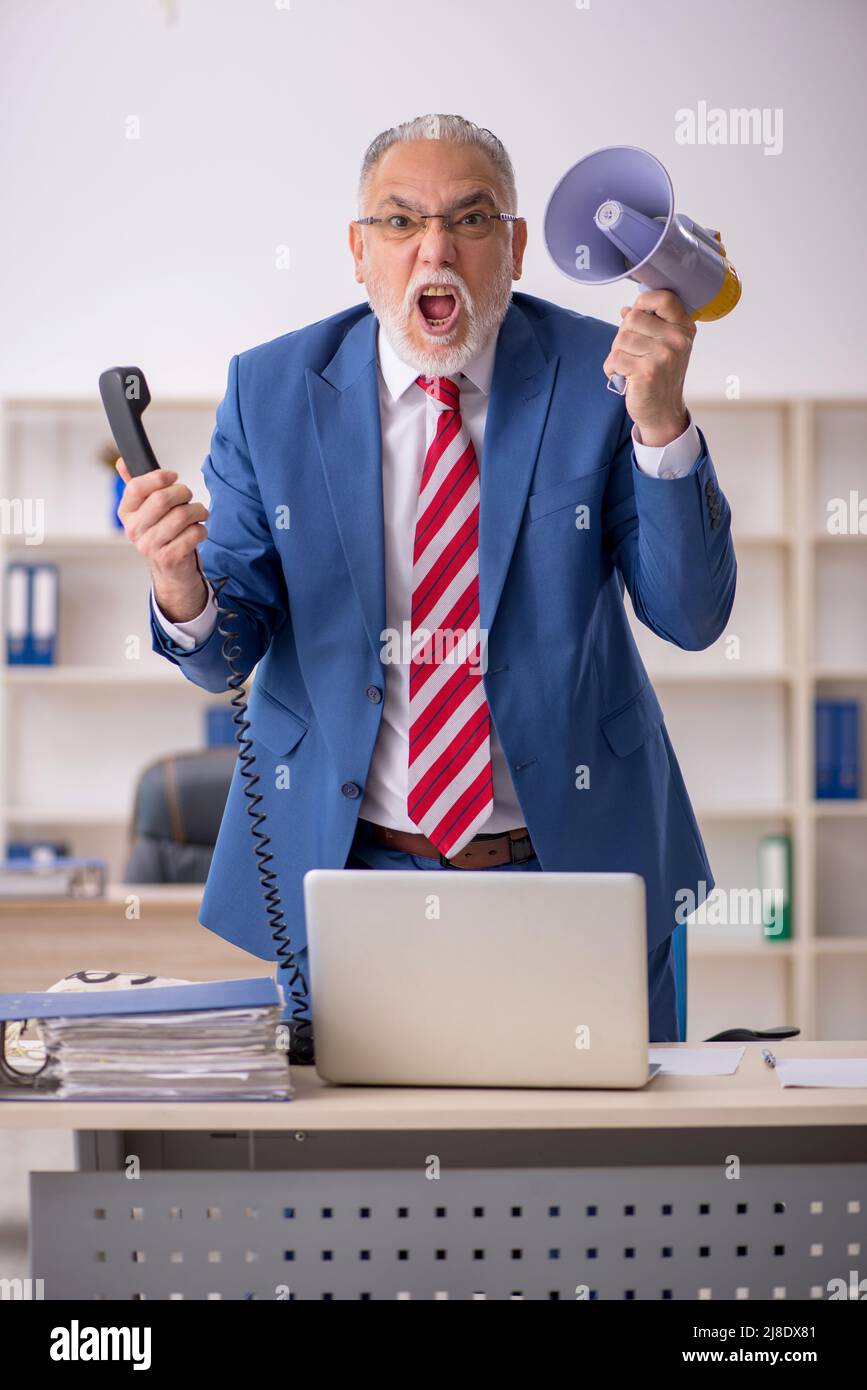 Angry old male boss holding megaphone in the office Stock Photo - Alamy