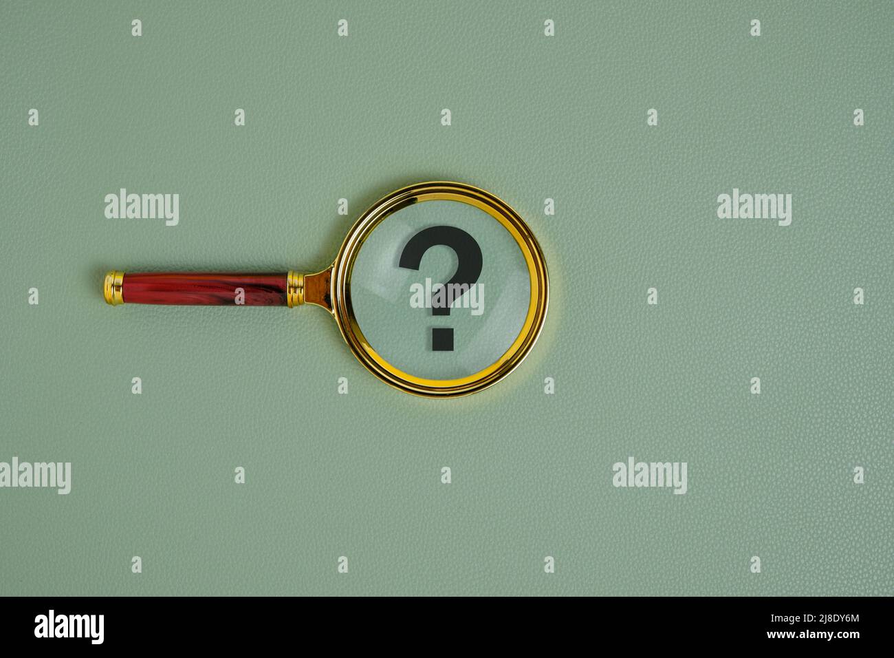 Question mark under magnifying glass, on green background Stock Photo ...