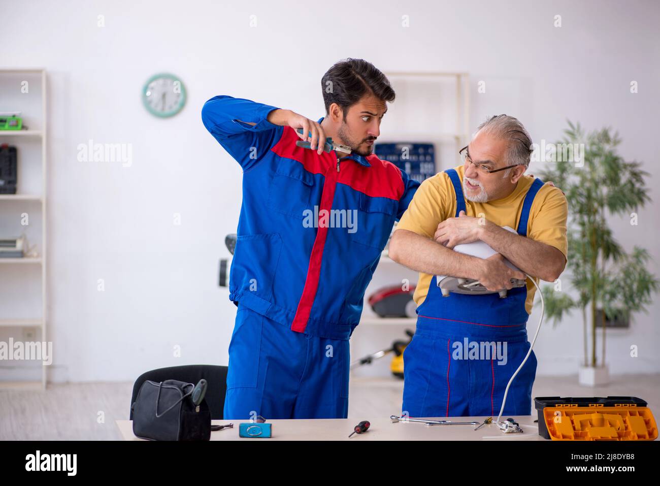 Two repairmen working at workshop Stock Photo - Alamy