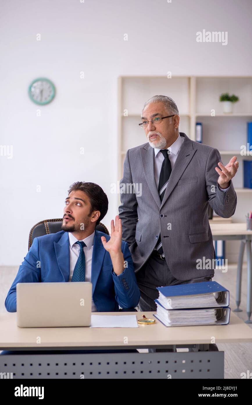 Old boss and young employee working at workplace Stock Photo - Alamy