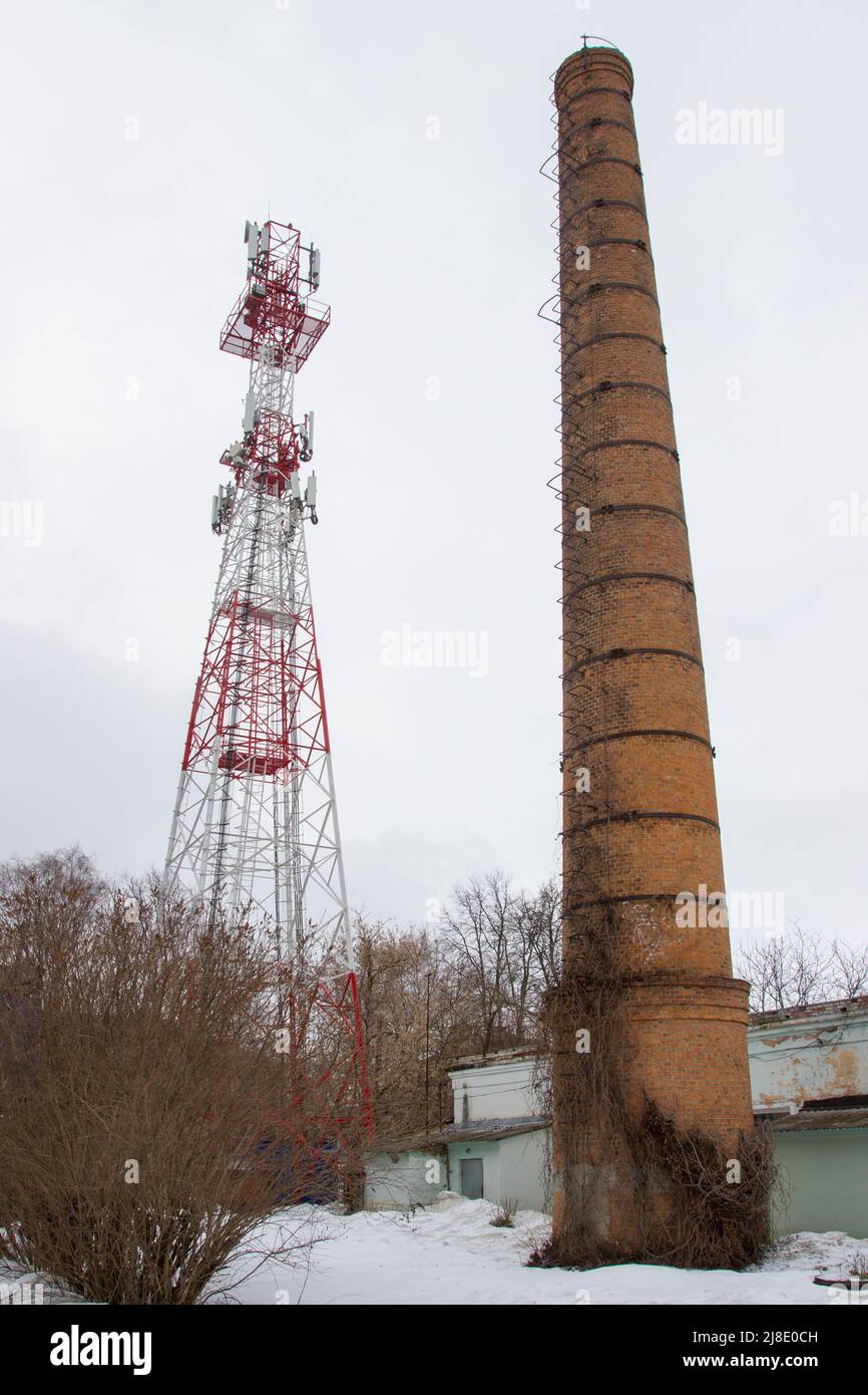 Old and new. A cell tower on the background of a brick chimney of an ...