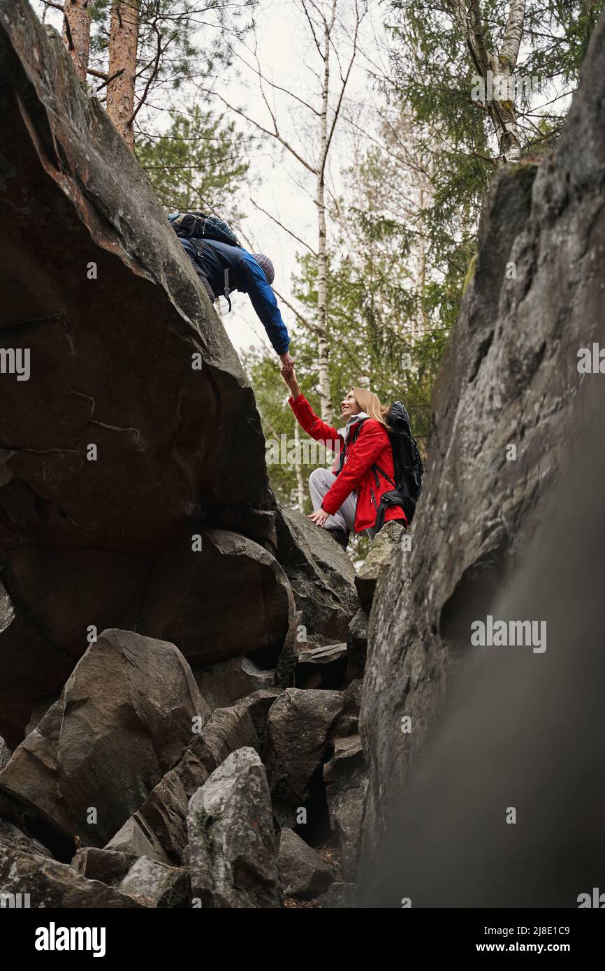 Lady supporting man trekker during descent from rock Stock Photo - Alamy