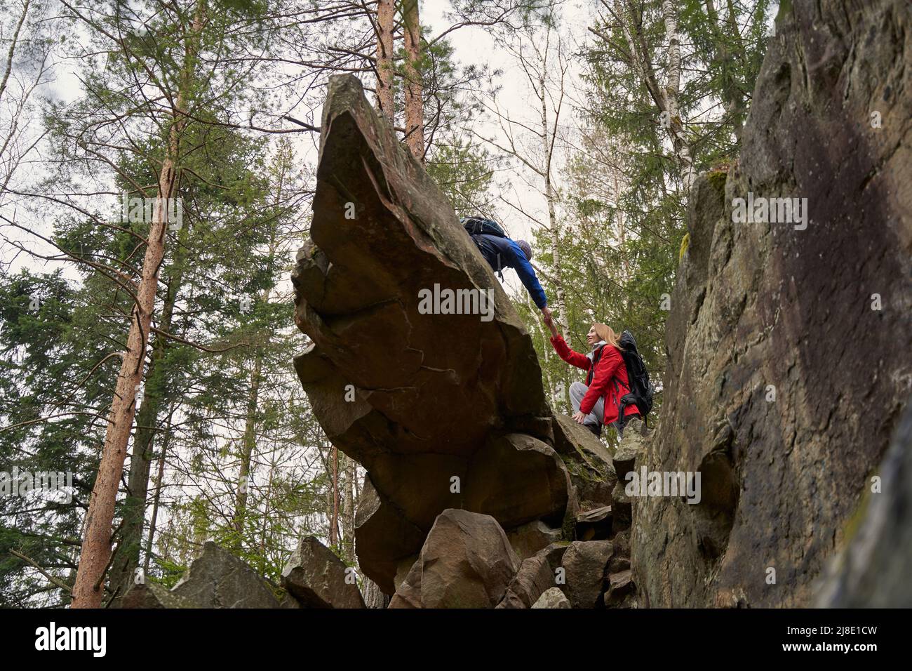 Female hiker helping man climb down from cliff Stock Photo - Alamy