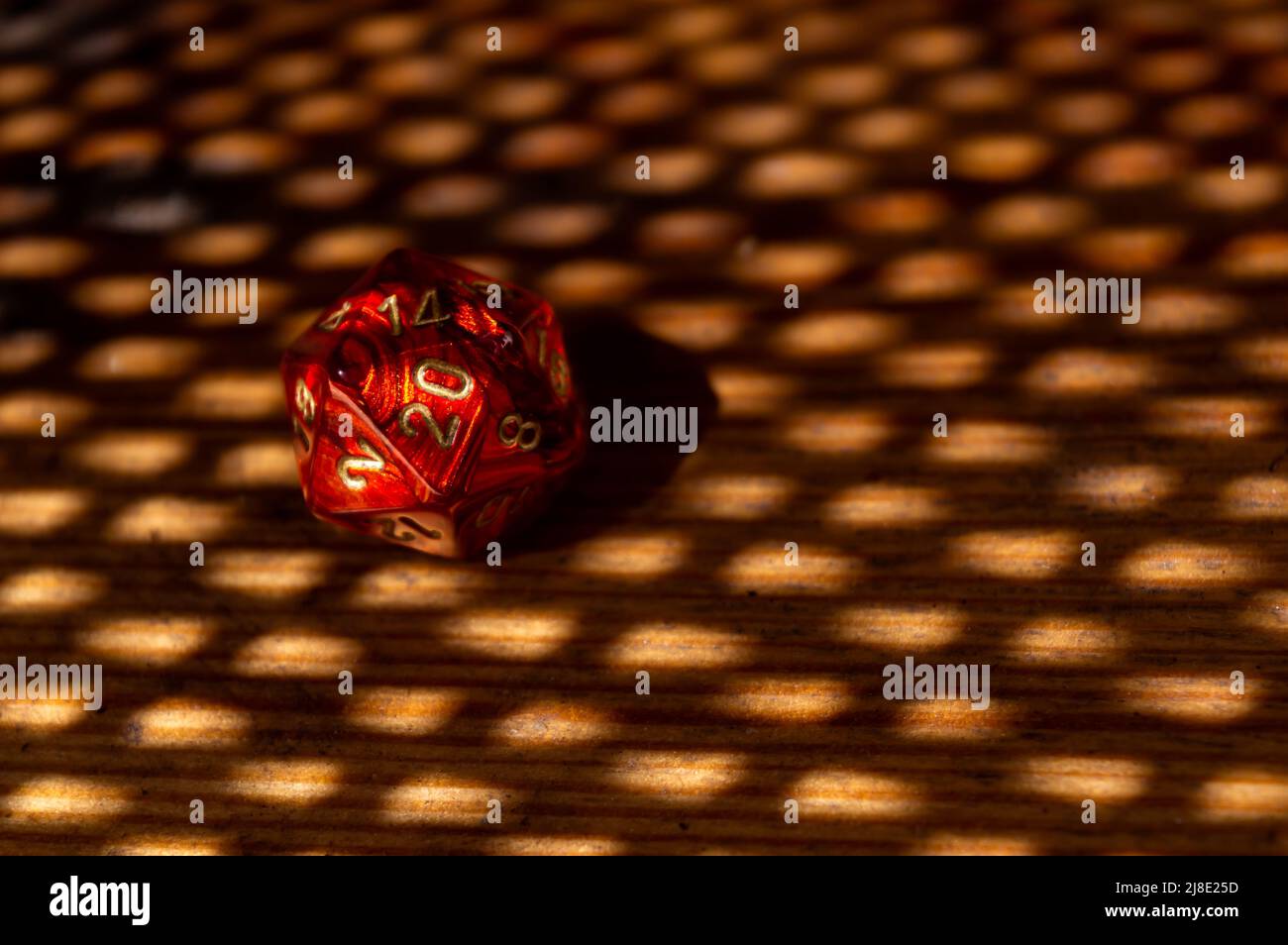 Close-up image of a red 20-sided role-playing die and pattern of light ...