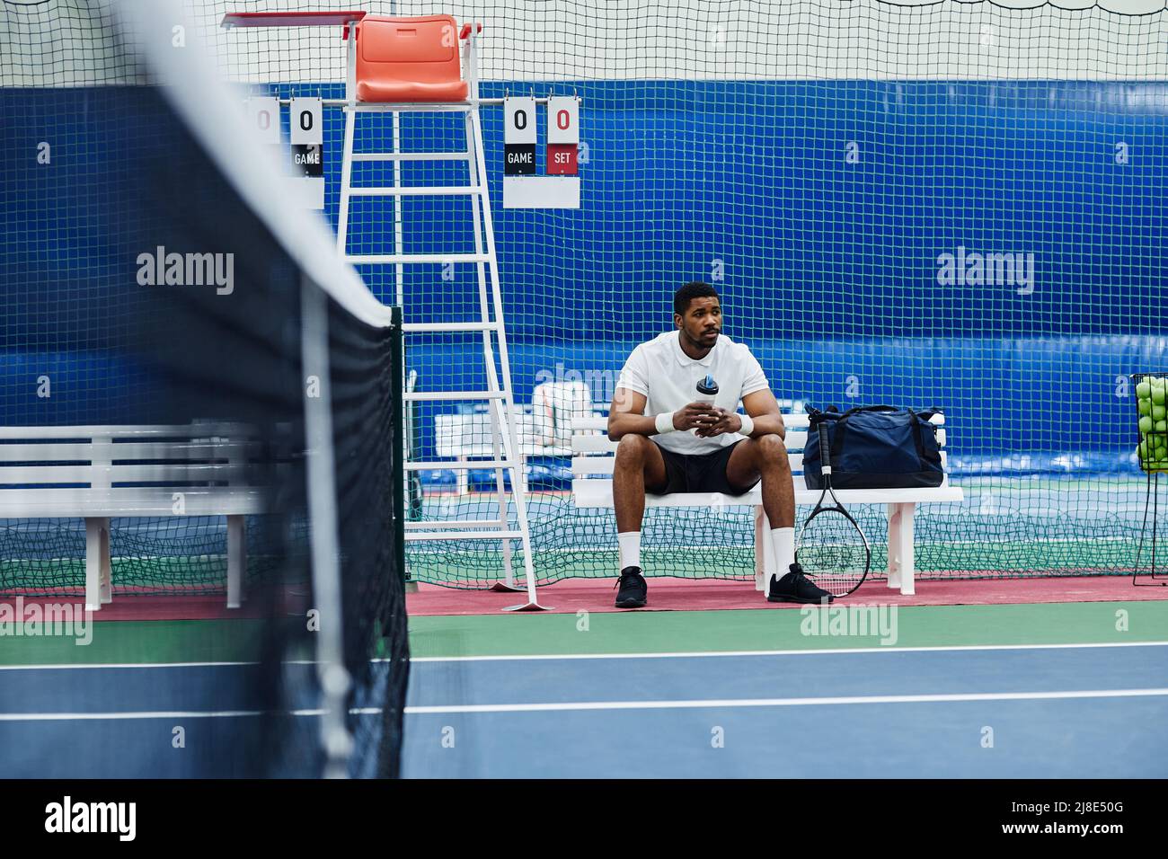 Wide angle shot of professional black sportsman sitting on bench in ...