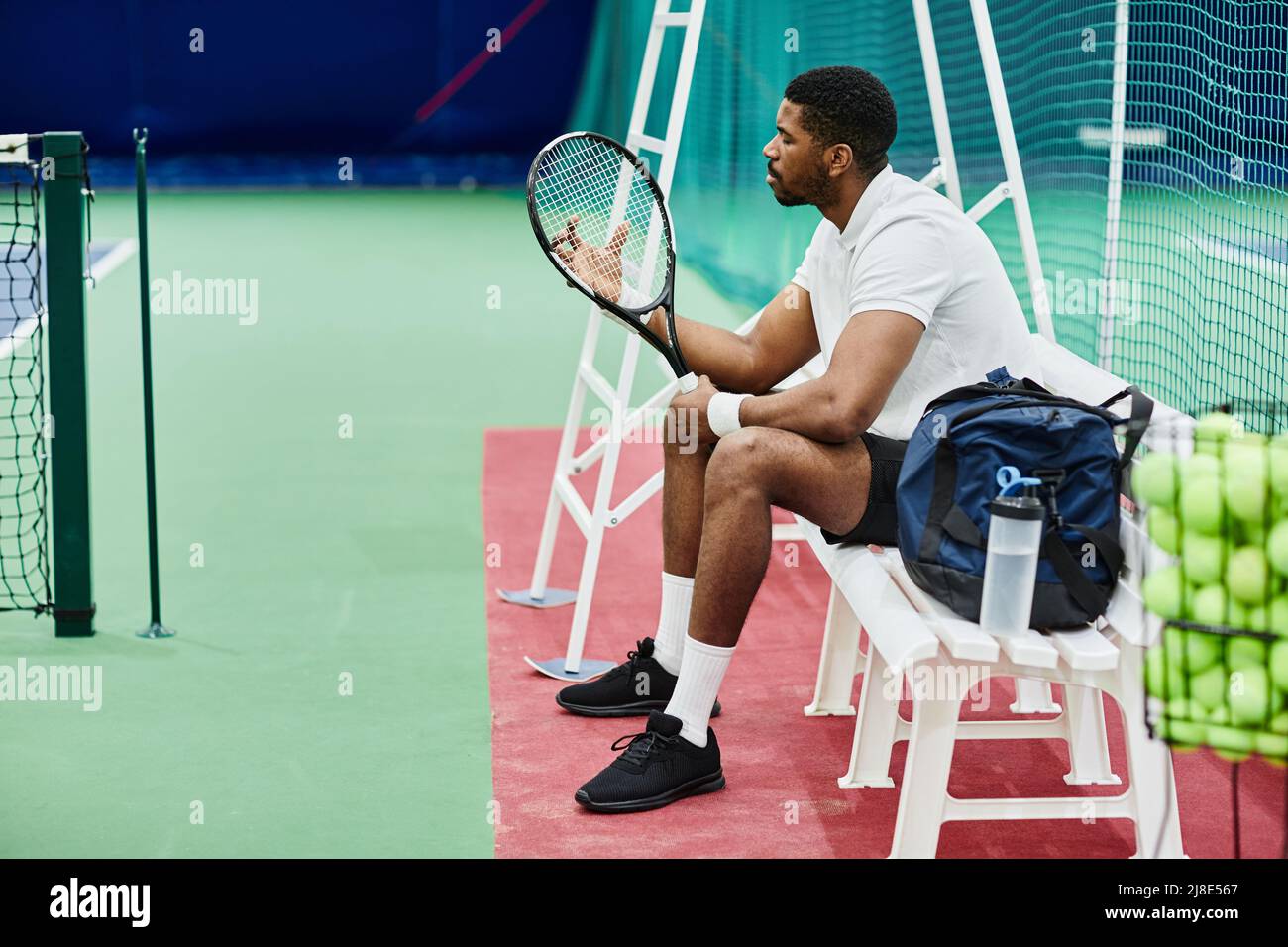 Side view portrait of professional tennis player holding racket while ...