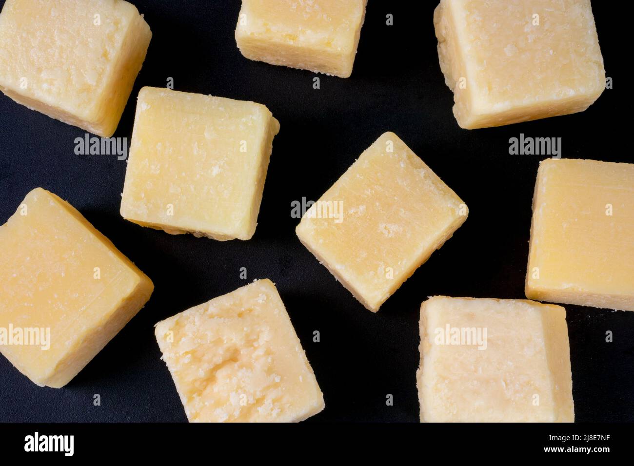 Parmesan cheese cubes on black background. Grana padano hard cheese ...