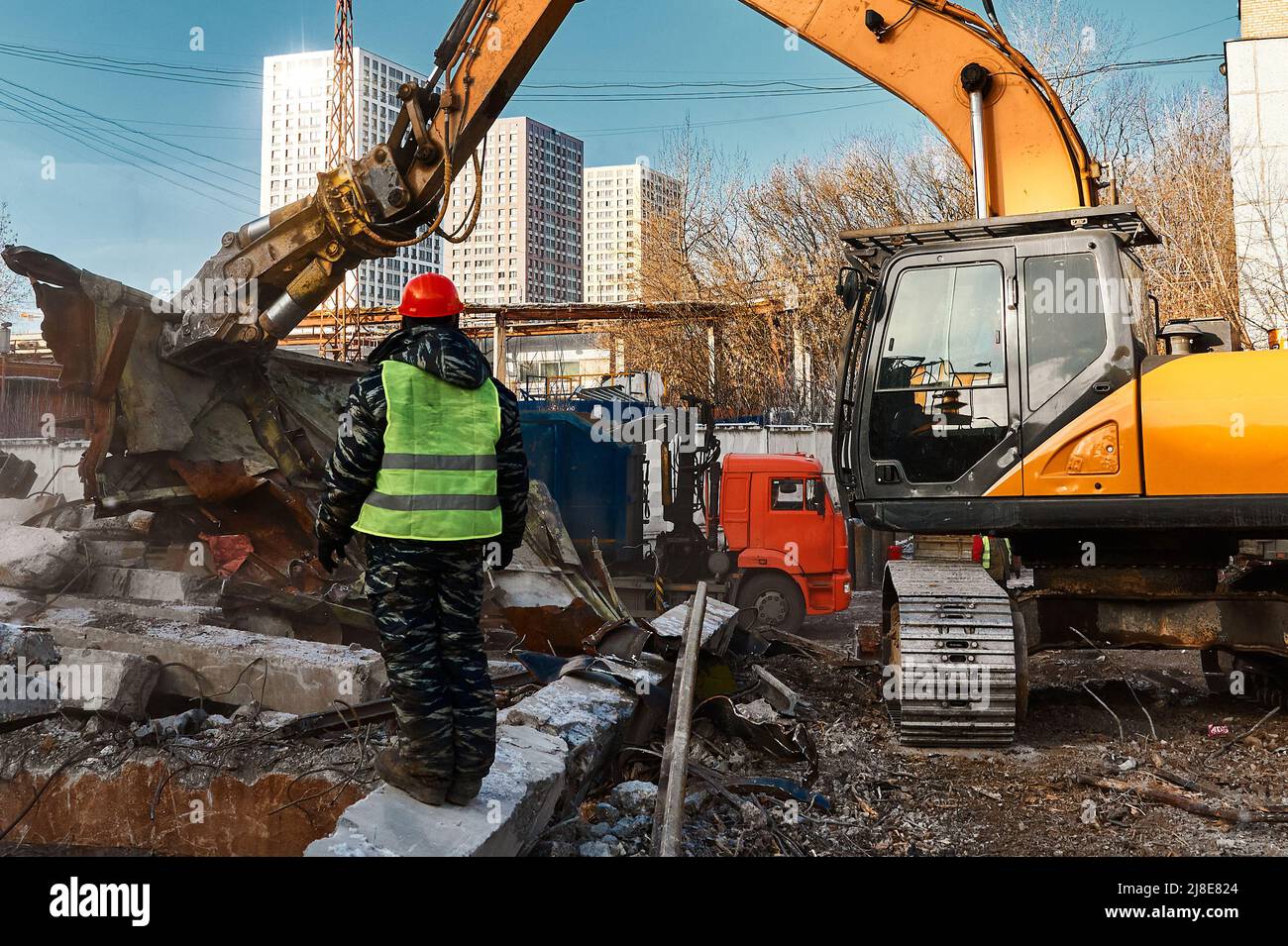 Excavator destroyer removes debris under worker control Stock Photo - Alamy
