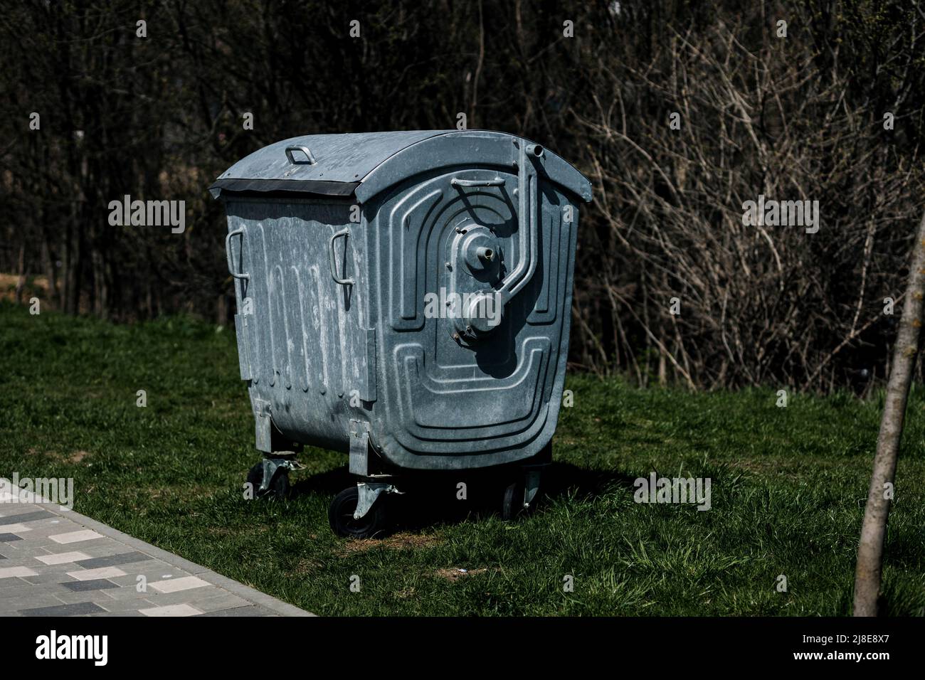 Metallic wheel trash can in park. Mobile trash can Stock Photo - Alamy