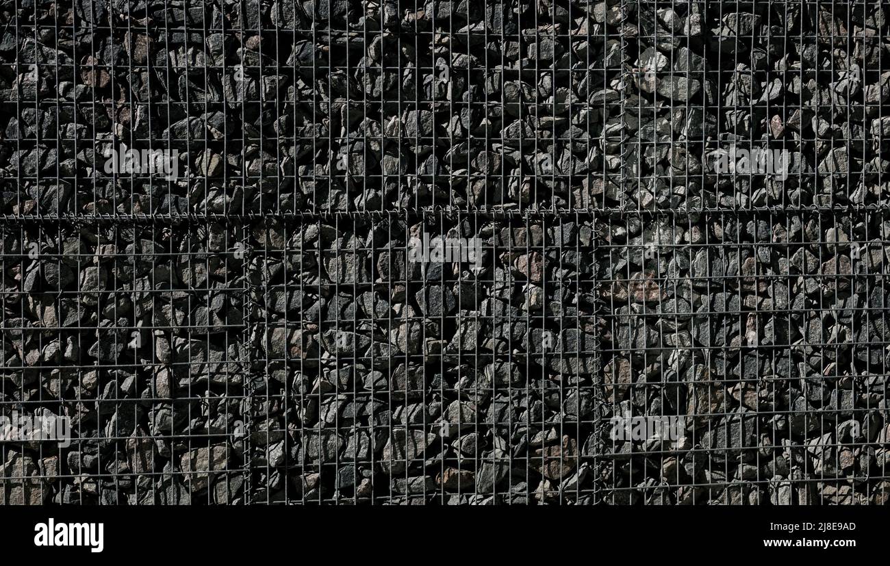 Wall with a grid of stones and metal wire. Decorative fence of bulk ...