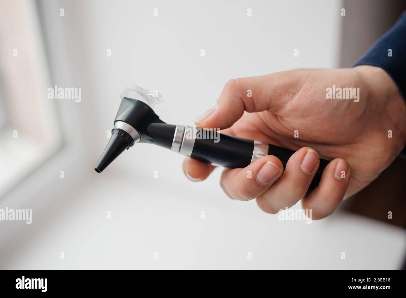Otoscope on a white background in the hand of an otolaryngologist ...