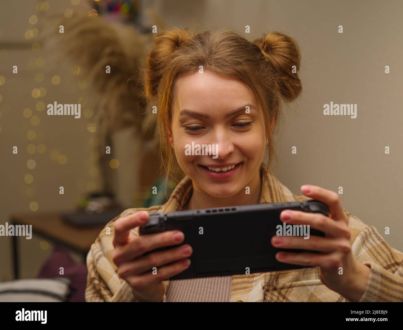 Close-up. Smiling girl gamer with a portable game console in her hands ...