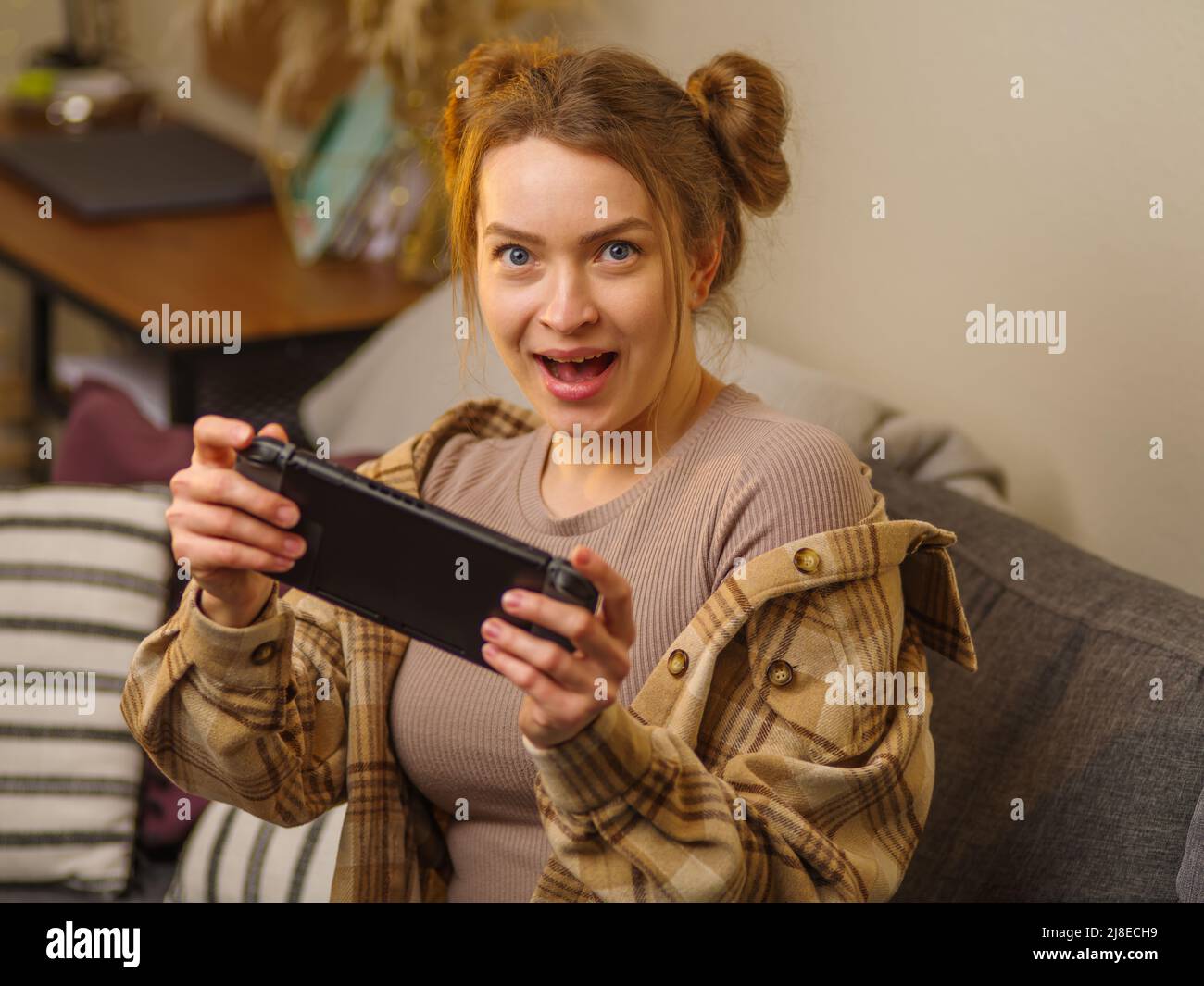 Girl gamer emotionally plays a video game on a portable game console ...