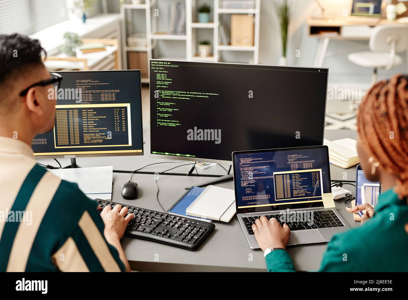 High angle of two IT developers using computers while reviewing code in ...