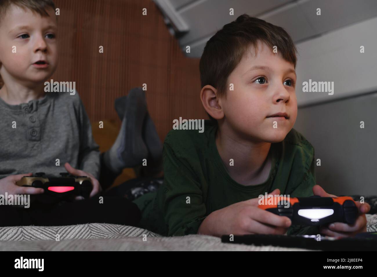Kids playing video games at home on the bed at night. Boys using game ...