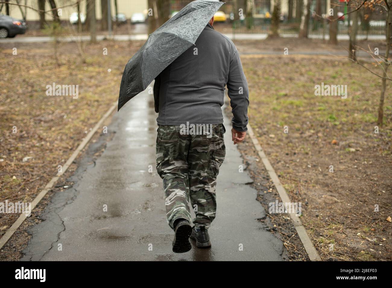 Man with black umbrella. Man walks down street in rain. Man in bad ...