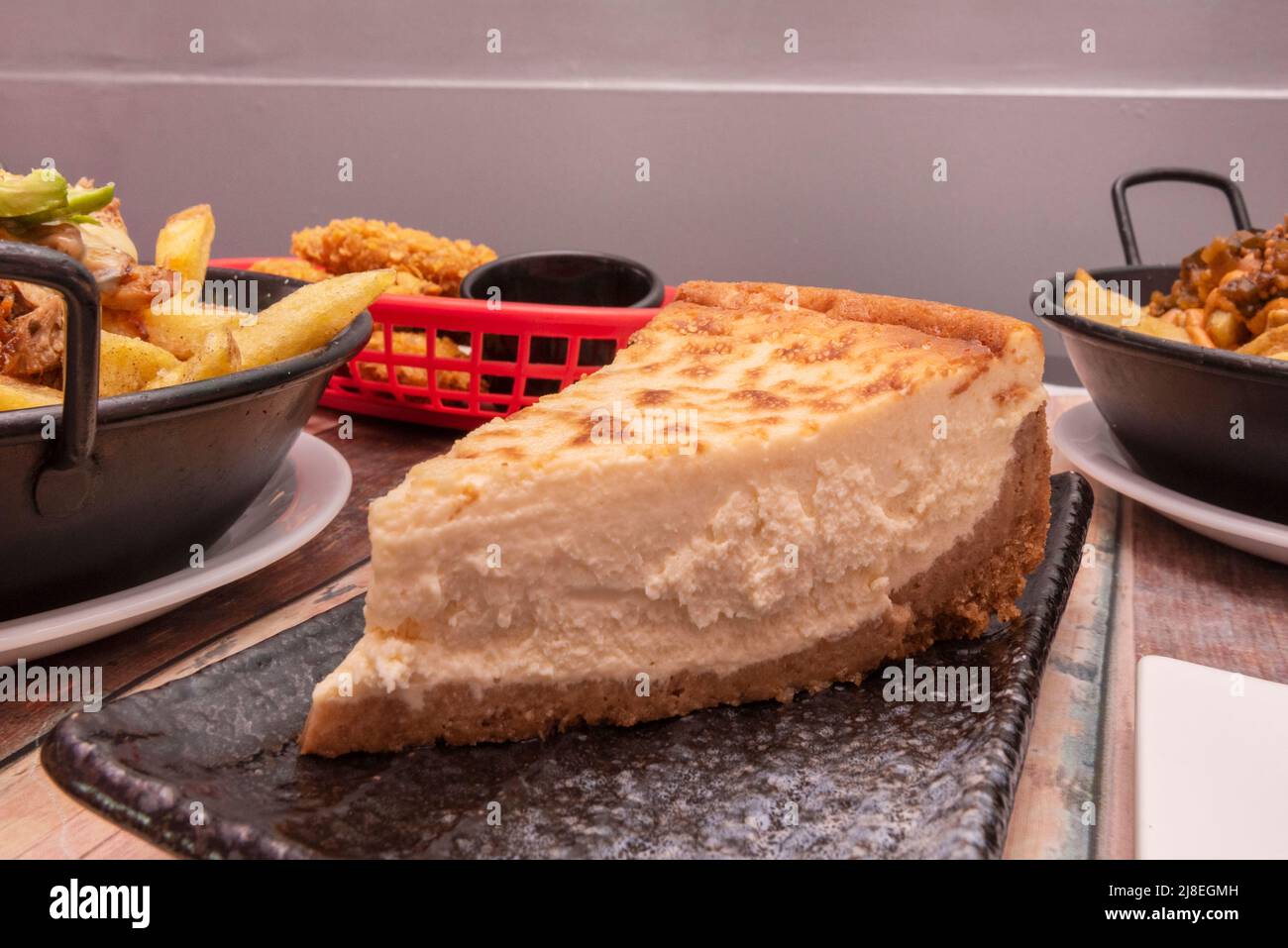 Slice of cheesecake a sponge cake between fast food dishes Stock Photo ...