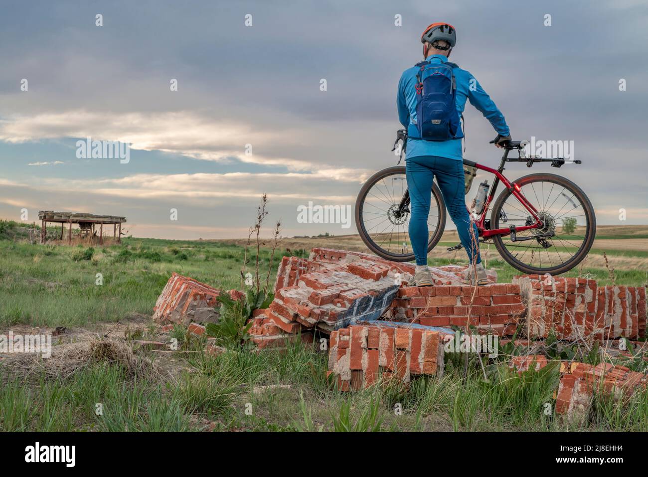 male cyclist with a gravel bike at remains of a silo and farm building ...