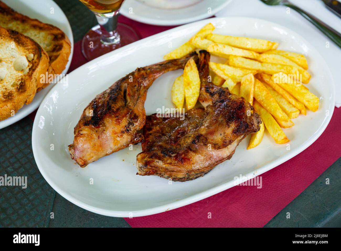 Grilled rabbit with vegetable garnish of fried potatoes Stock Photo - Alamy
