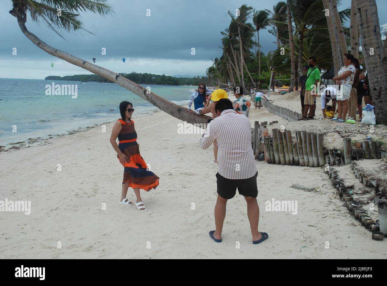 Tourists posing for photographs on palm tree, Bulabog Beach, Boracay ...