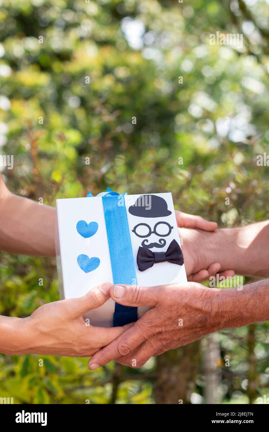 Vertical photo of hands of a young man giving a gift to his father who ...