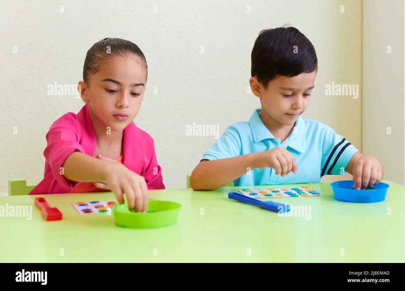 Preschool children playing with puzzle on a desk Stock Photo - Alamy