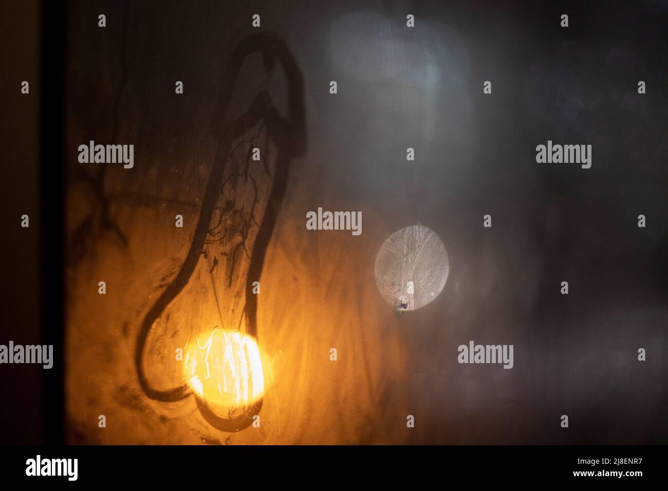 Drawing on wet glass. Foggy window. Warm light is reflected in surface ...