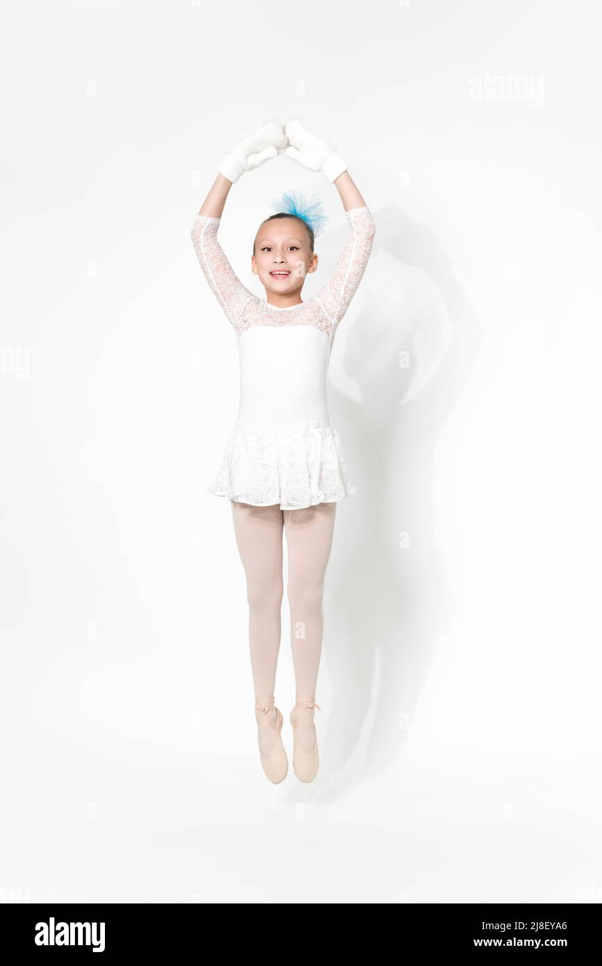 Girl ballerina in white ballet tutu skirt, blue bow in hair and white ...