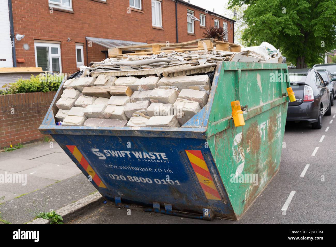 skip loaded with building bricks and rubbles on roadside London England ...