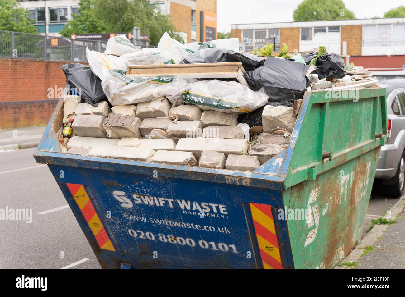 skip loaded with building bricks and rubbles on roadside London England ...