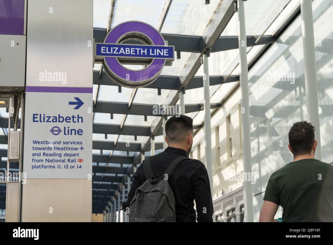 two passengers walk past an ELIZABETH LINE logo, new crossrail train ...