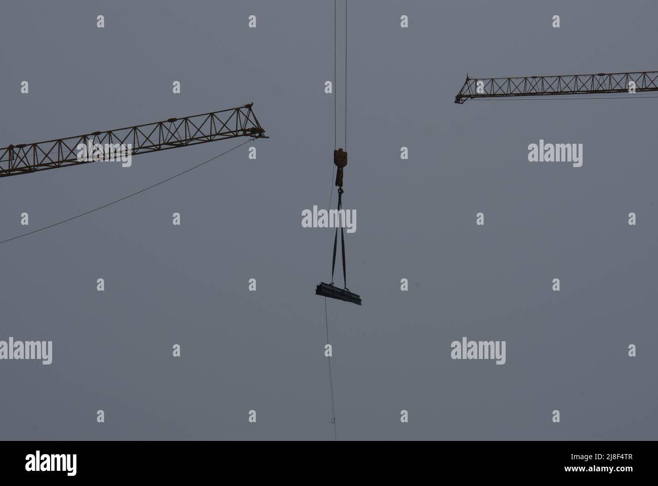 Tower cranes working on a construction site lifts a load at high-rise ...