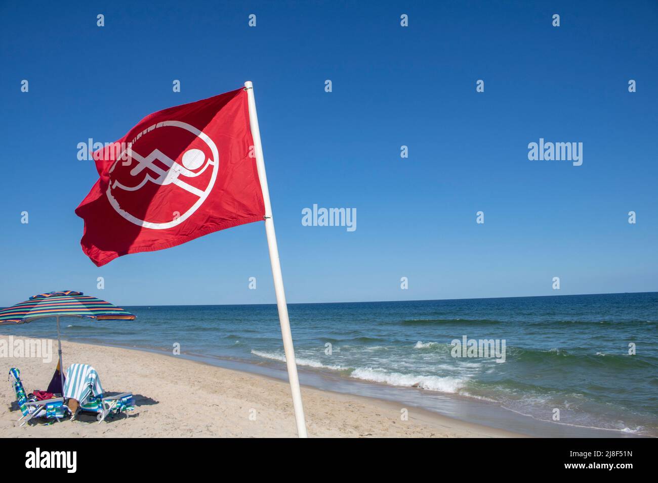 Red and white no swimming symbole icon on a beach flag spiked into the ...