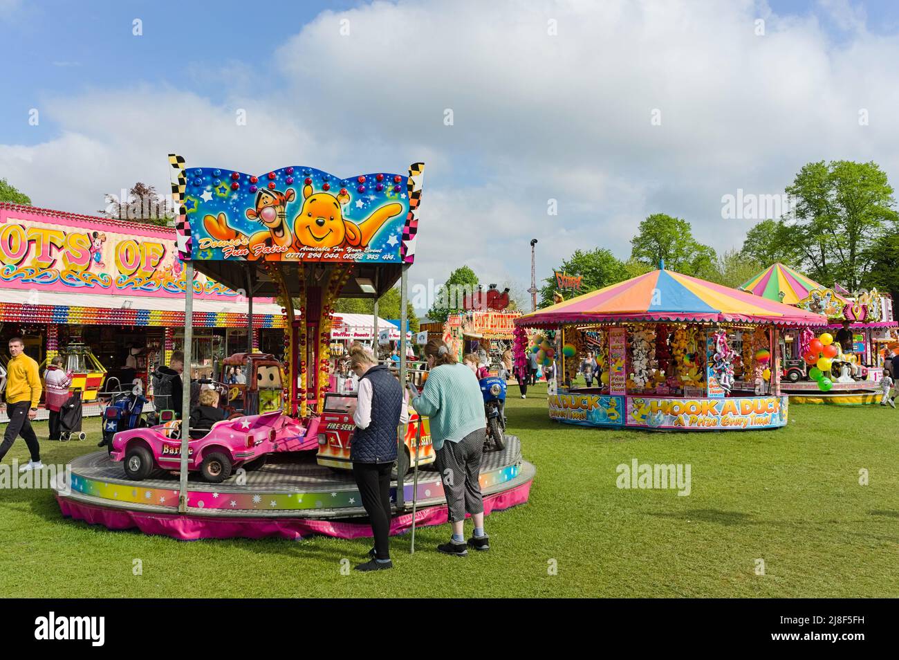 Children`s amusement rides at the May fair in the park on a sunny day ...