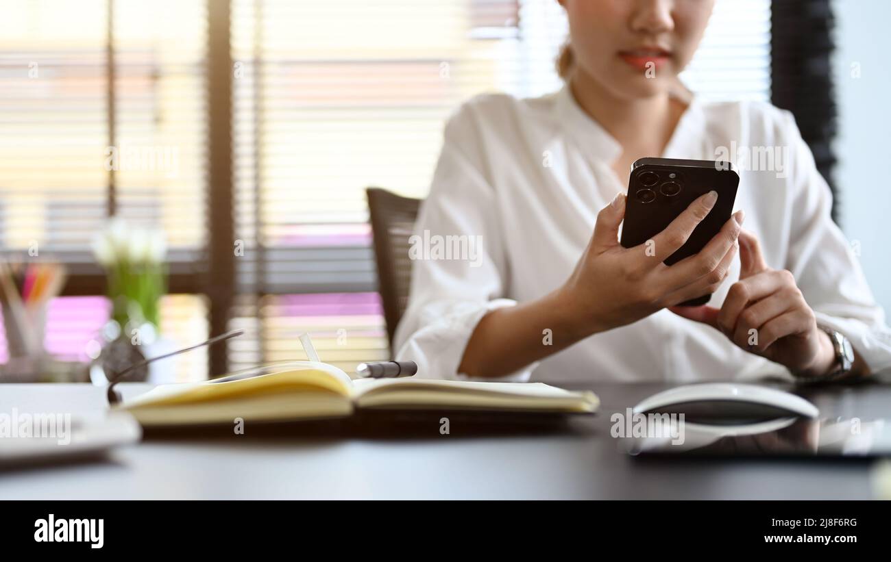 Beautiful Asian businesswoman working at her desk, using cellphone to ...