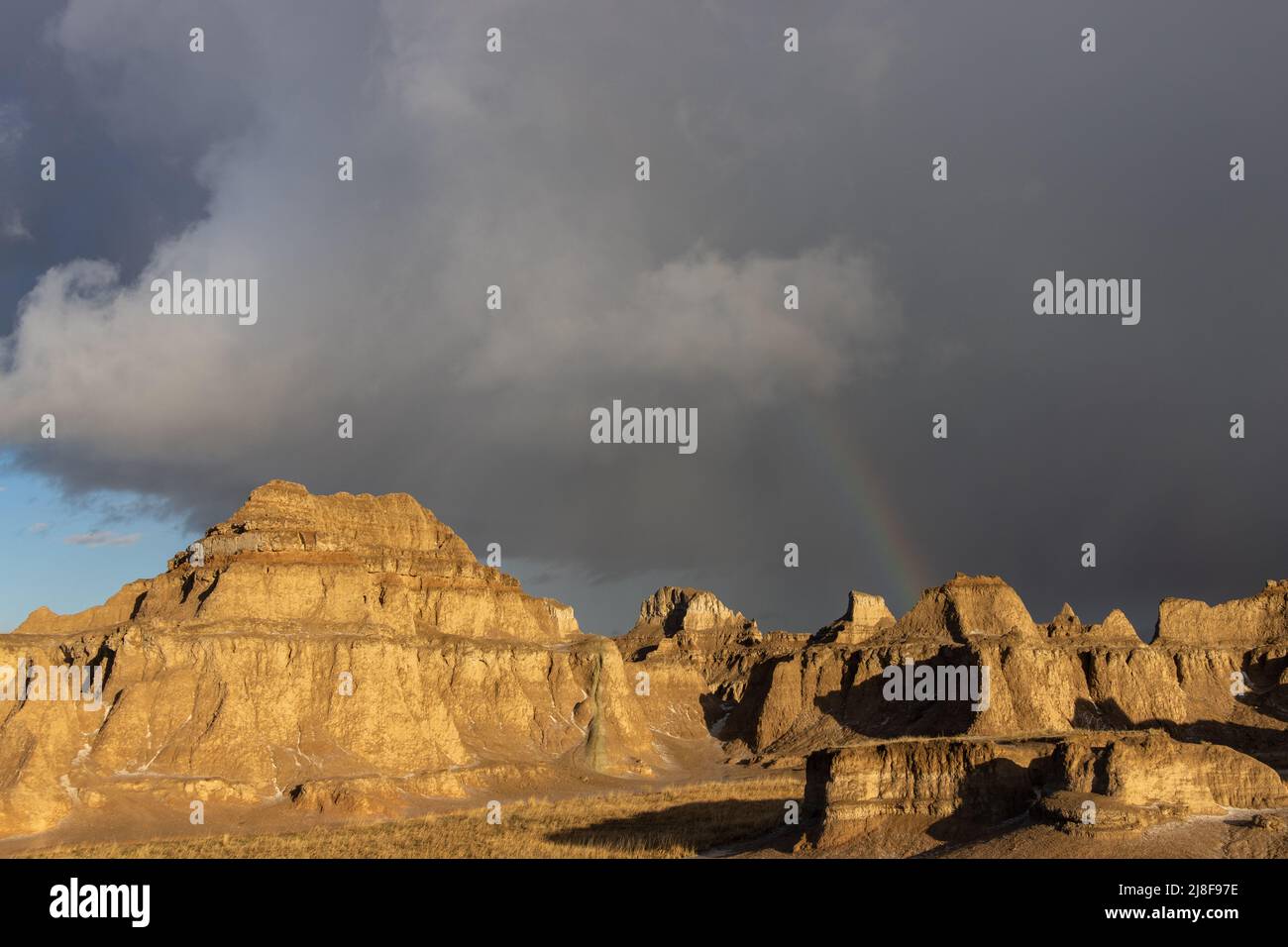 A rainbow is visible behind a rock formation at Badlands National Park ...