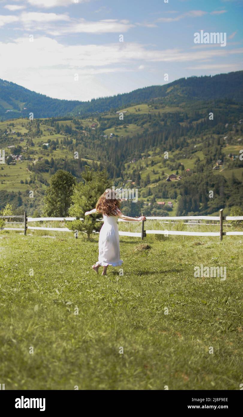 Happy young woman is turning round in the field. Freedom feeling in the ...