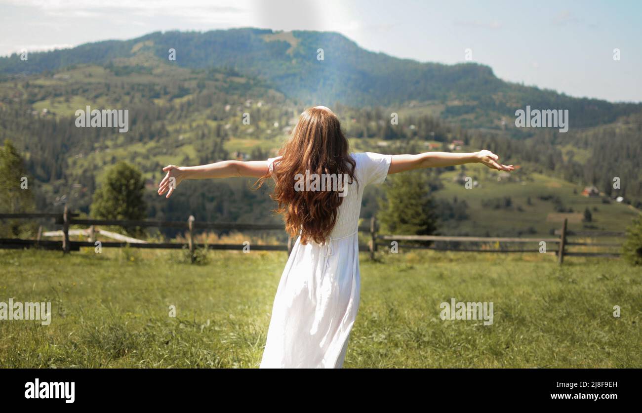 Happy young woman is turning round in the field. Freedom feeling in the ...