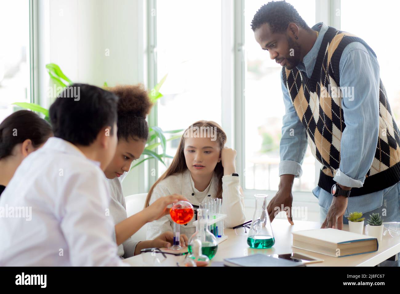 Young teacher teaching group student about science and test chemical ...