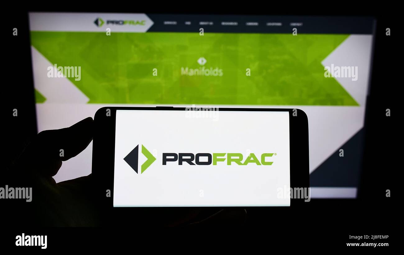 Person holding mobile phone with logo of American oil and gas company ...