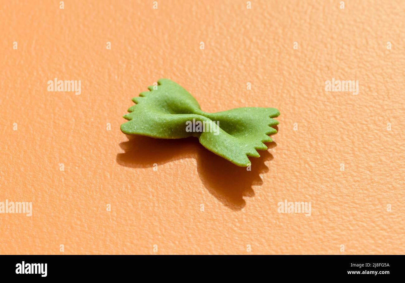 Single ribbon-shaped pasta isolated on orange background in bright ...