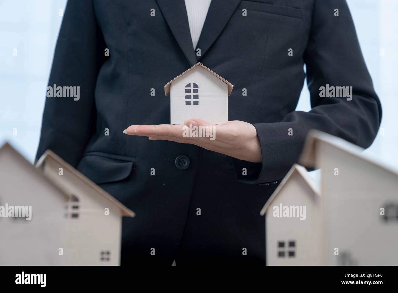 Real estate broker holding model residential house Stock Photo - Alamy