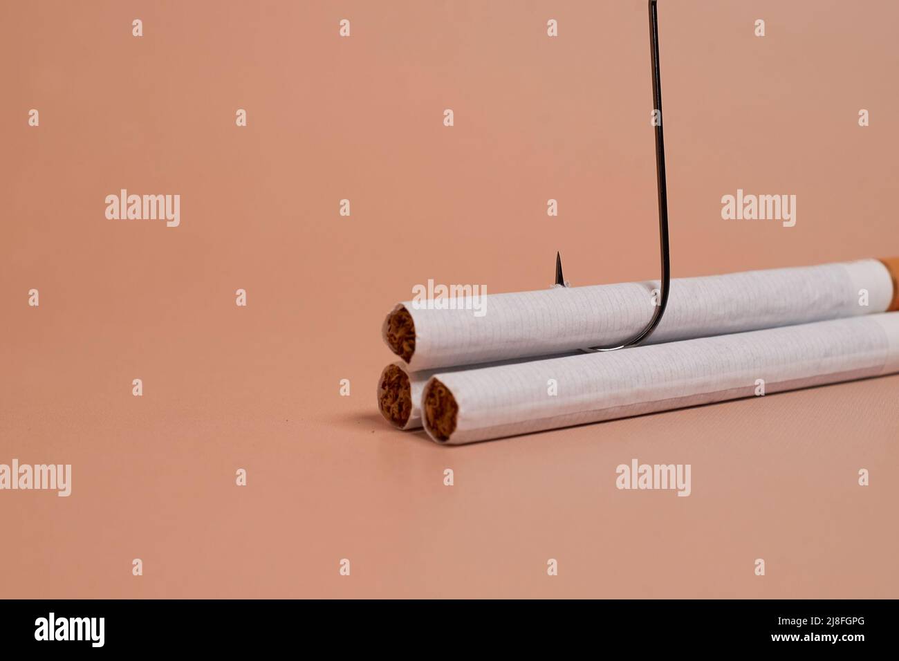Three cigarettes with a fish hook on a colored background Stock Photo ...