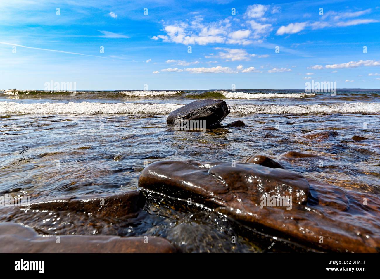 low perspective of wave over stone on beach Stock Photo - Alamy