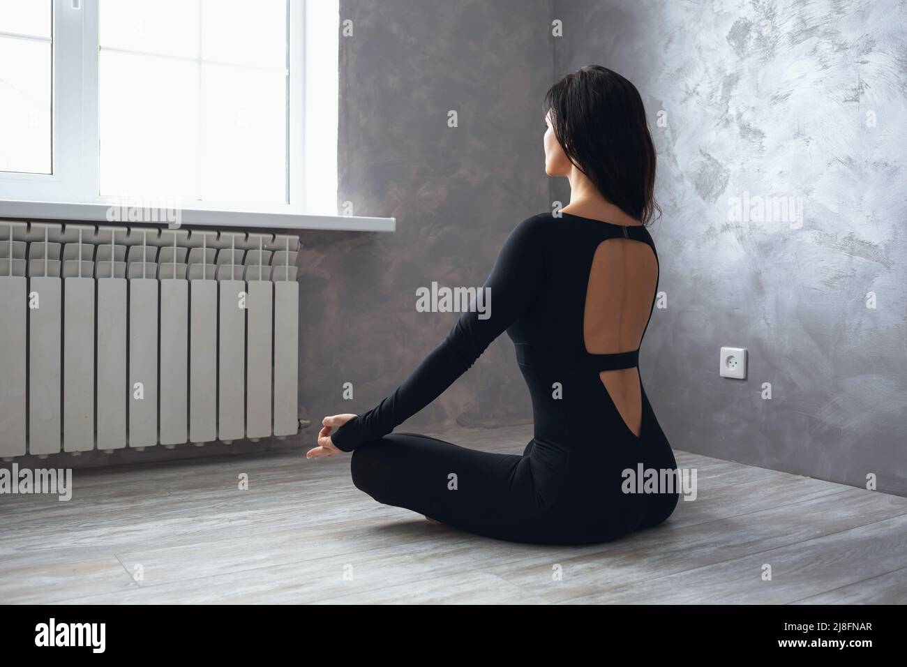 A woman practicing yoga, meditating in the lotus position, sits in a ...