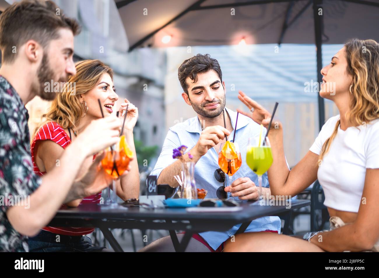 Four trendy young people get together carefree sitting and bonding at ...