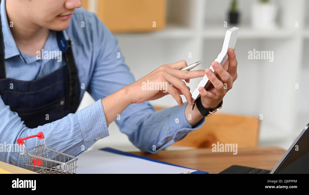 Asian man online seller using calculator while working at his home ...