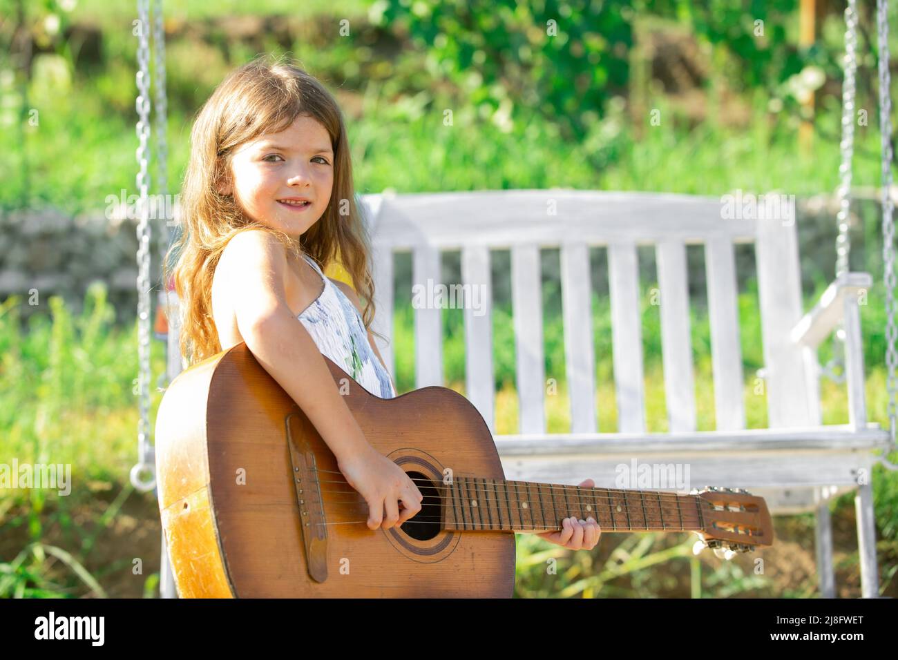 Happy smiling child girl play the guitar. Dreamy kids face. Smiling ...