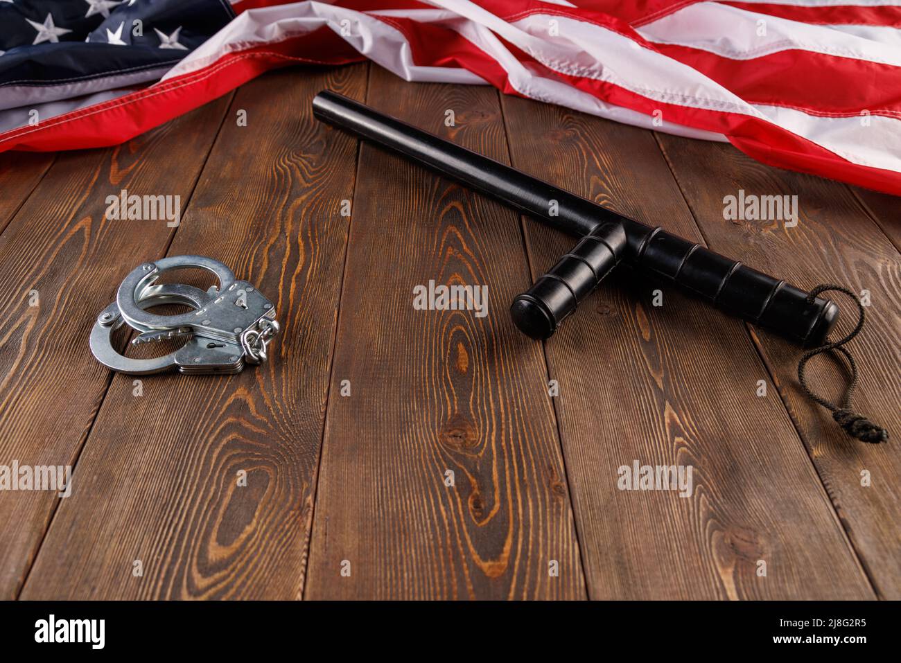 silver metal handcuffs and police nightstick near US flag on wooden ...