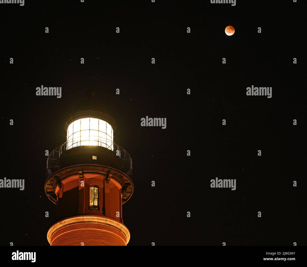 An eclipsed moon hangs over the historic Lighthouse in Ponce Inlet ...
